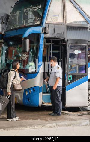 A double-decker bus driver is seen using a ladder to place passengers' luggage in the storage ...