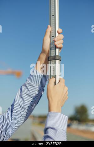 Worker is unfolding leveling rod on construction site Stock Photo - Alamy