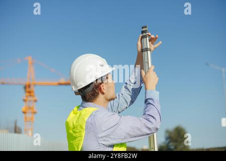Worker is unfolding leveling rod on construction site Stock Photo - Alamy