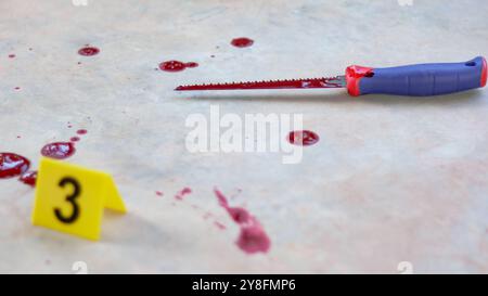 A bloodstained stainless steel handsaw lying on a concrete floor, with ...