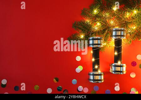 Red gym dumbbells and Christmas tree branches. Healthy fitness winter ...