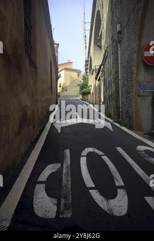 Narrow alley on a slope next to a bridge with a stop sign on the ground ...