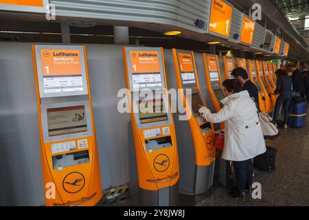 Passengers using a set of auto check-in machines of Lufthansa inside ...