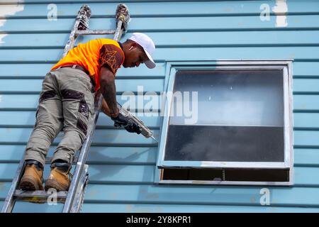 Painter sealing around window frame of old wooden home being repainted ...