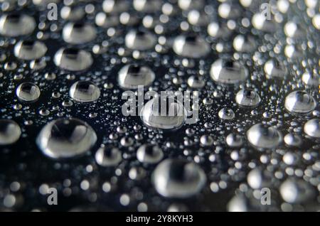 Side view of raindrops forming patterns on a smooth surface of metal ...