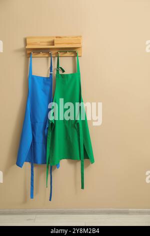 Two chef's aprons hanging on beige wall Stock Photo - Alamy