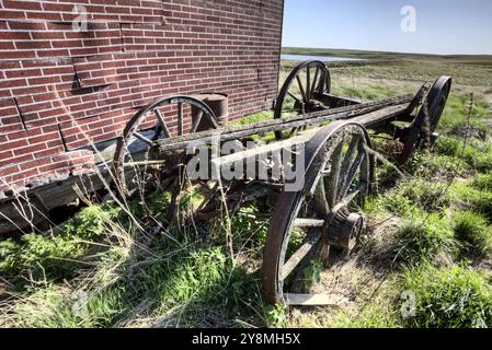 A closeup shot of an old wagon wheel and purple flowers leaned on a red ...