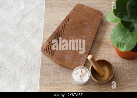 Sadhu board with Tibetan bowl and aroma stick on pouf in room, top view ...