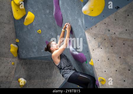 Sporty woman training at bouldering gym without special climbing ...