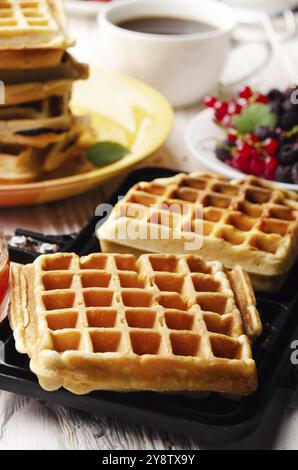 Belgian waffles on cast skillet with stacked ones and coffee aside ...