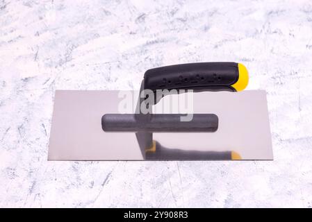 Trowel with black-yellow handle to the smoothing of plaster on white ...