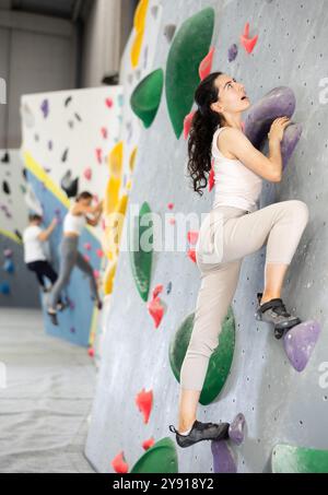 Girl in sportswear practicing rock climbing on climbing wall Stock ...