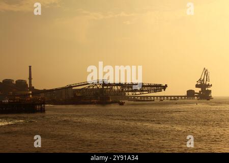 Jetties and gantry cranes for loading minerals onto ships in port ...
