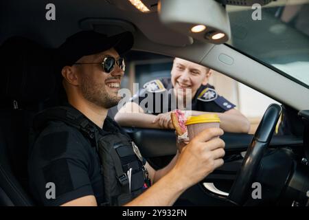 Patrol police officers diverse team sitting in car having coffee break ...