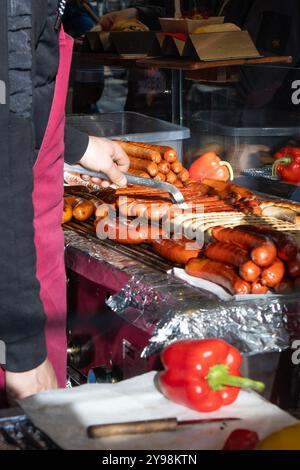 Chef grilling fresh meat sausages on big round hanging grill - close up ...