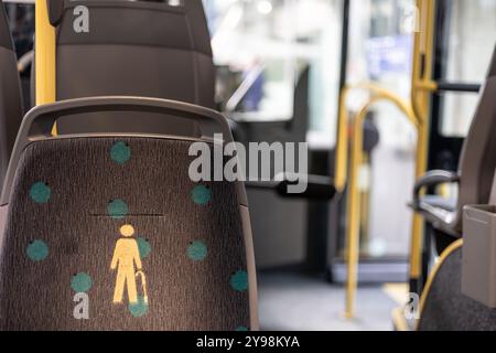 The interior of a city bus shows rows of seats with clear markings for ...