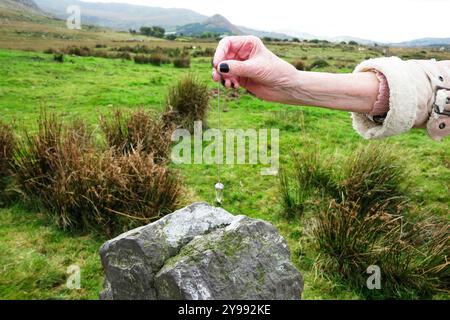 Female dowsing a standing stone using a crystal pendulum at the Merry ...