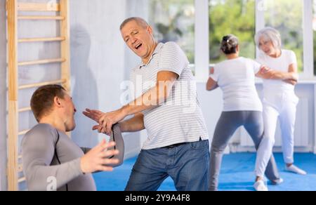 Old man twisting her opponent's arm during self-defense classes Stock ...