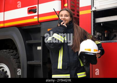 Firefighter in uniform using portable radio set near fire truck ...