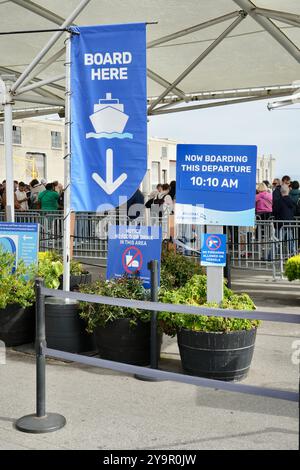 People at boat boarding-point sign and marker for the start of the Aros ...