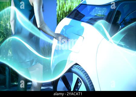 Blue wave against woman charging electric car at charging station Stock ...