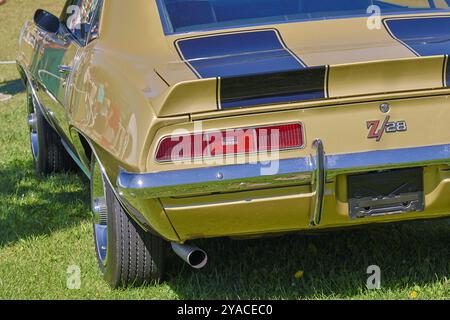 Restored gold chevrolet camaro z28 with black racing stripes is parked ...
