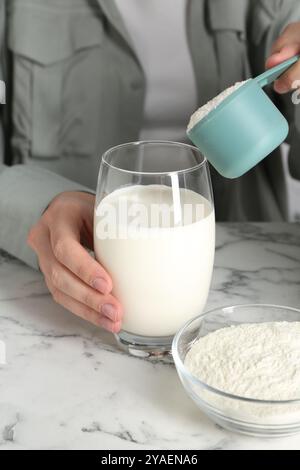 Making protein cocktail. Woman adding powder into glass with milk at ...