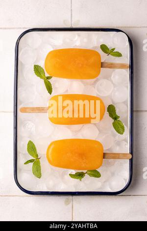 Horizontal image of orange homemade ice cream in cone, on blue and pink ...