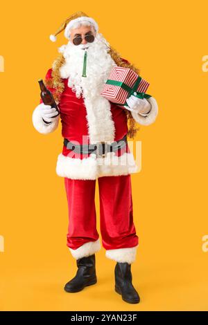 Cool Santa Claus with beer and Christmas gift on yellow background ...