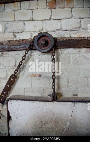 Rusted metal pulley system with chains mounted on a weathered brick ...