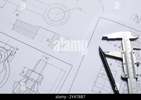 Different engineering drawings, vernier caliper and pencils on wooden ...