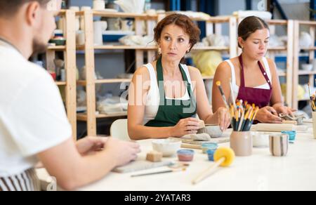 Three pottery workshop workers sculpt from raw clay Stock Photo - Alamy
