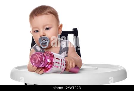 Cute little baby with pacifier and microphone in high chair on white ...