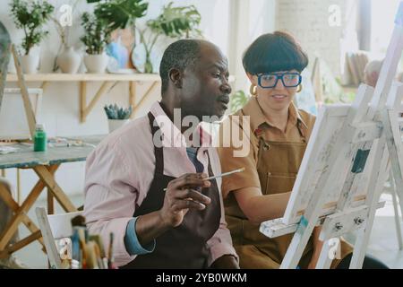 Happy female African-American painter with roller and cute Australian ...