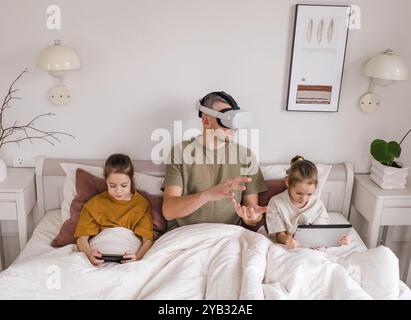 Happy kids using virtual reality headsets and pointing up with finger ...