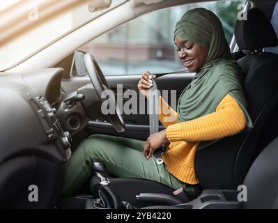 Smiling woman fastening seatbelt in car, prioritizing road trip safety ...
