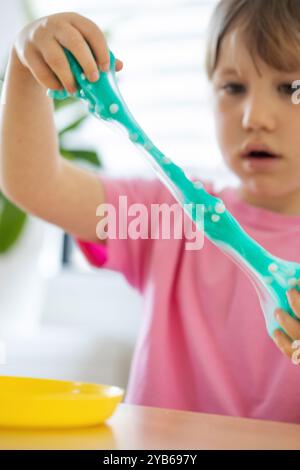 A child playing with bright, blue slime, enjoying a fun and creative ...