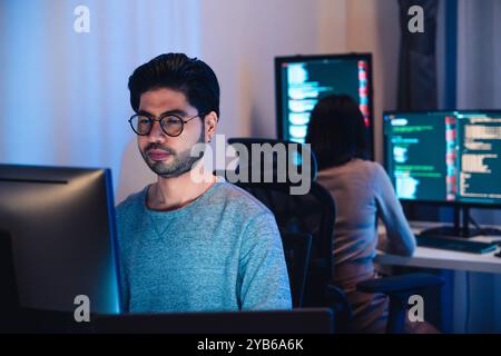 Asian software developers working on multiple screens displaying code ...