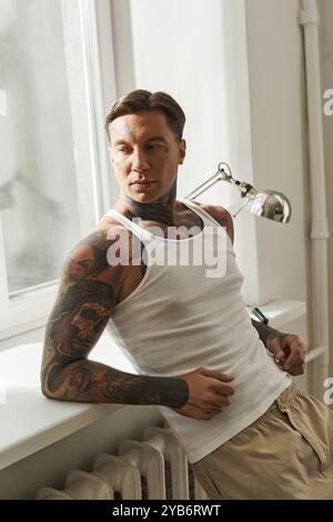 Young man leans against window of modern building Stock Photo - Alamy