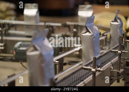 roasted coffee beans in package on conveyor belt in factory. Coffee ...