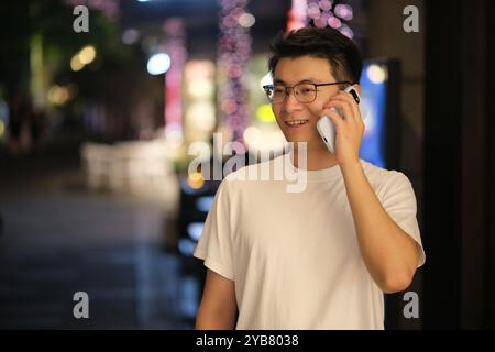 Asian man on phone call with business professionals working in a modern ...