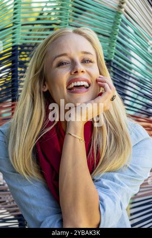A stylish blonde woman models a chic denim ensemble against a warm ...