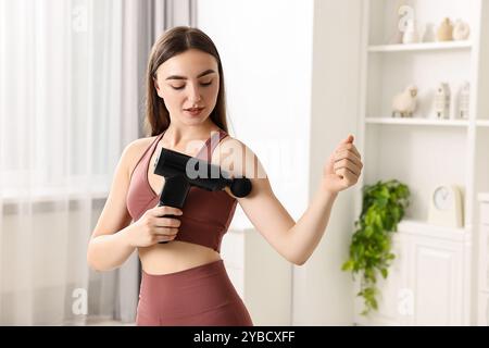 Young woman using percussive massage device at home Stock Photo - Alamy