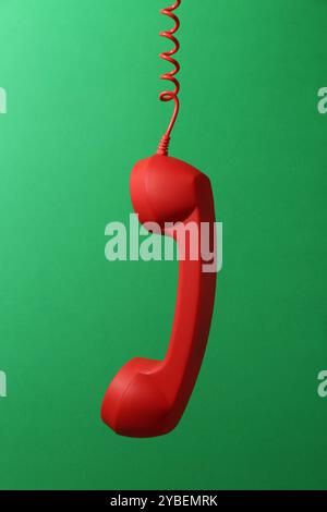 Red corded telephone handset hanging on white background. Hotline ...