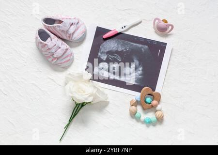 Composition with baby shoes, sonogram image, pregnancy test and toys on ...