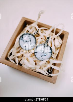 A closeup of a pair of handmade silver earrings isolated on a black ...