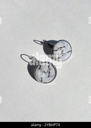 A closeup of a pair of handmade silver earrings isolated on a black ...