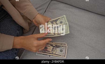 Young woman at home counts dollar money cash with smartphone checks ...