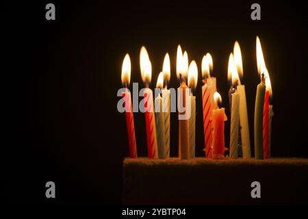 Series of small lighted candles on a black background Stock Photo - Alamy