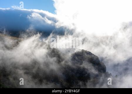 Misty mountain slope with sunlight breaking through clouds against a ...